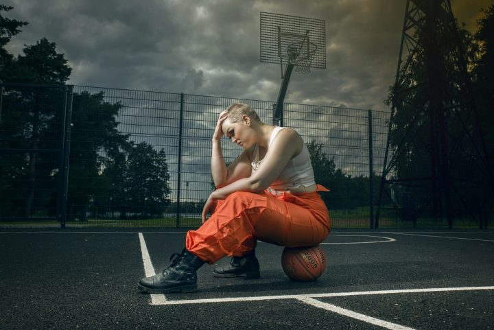 Lady Prisoner Sitting On A Basketball Under Dark Clouds While Holding ...