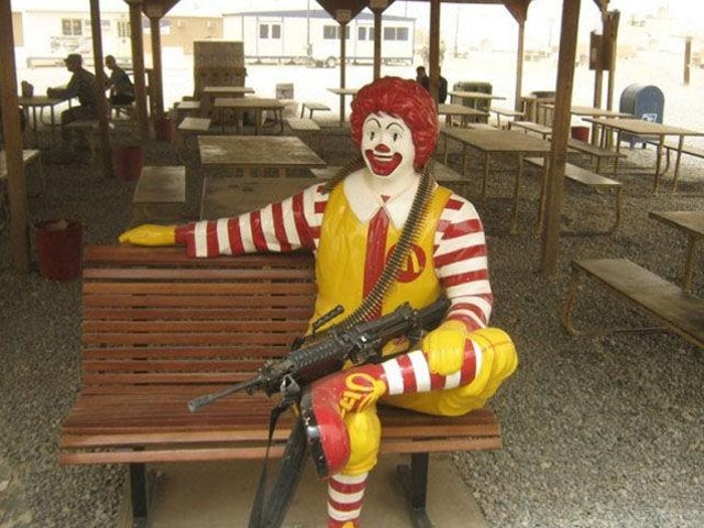 A Statue Of Ronald Mcdonald Holding An M249 Light Machine Gun At A